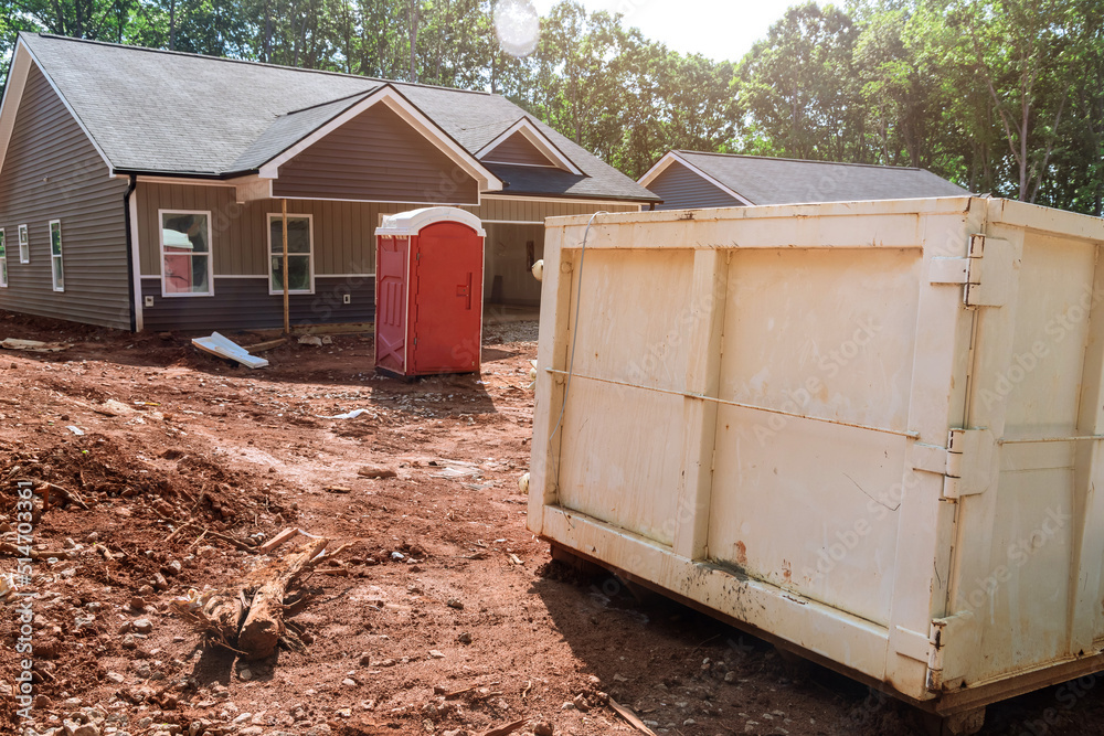 Construction garbage dumpster and portable restroom in new house under ...