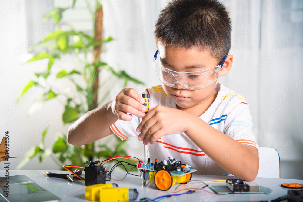 Little child tighten the nut with a screwdriver to assemble car toy ...