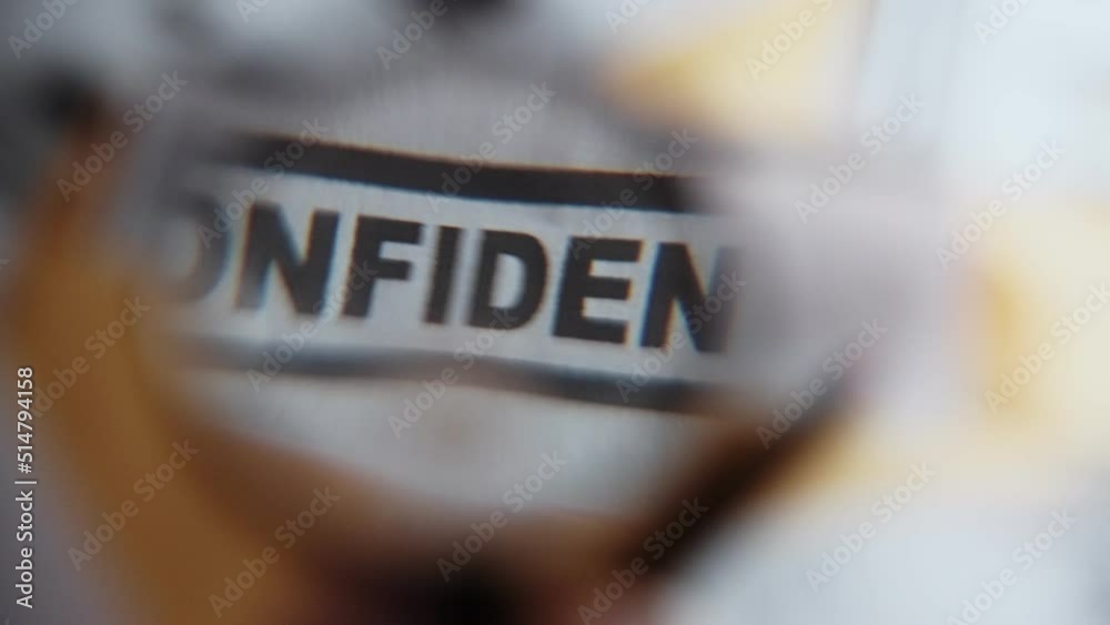 Confidential stamp revealed by magnifying glass moving across paper or ...