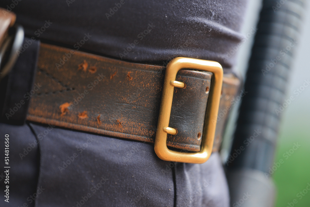 A law enforcement officer wears a duty belt, with a pistol, handcuffs ...