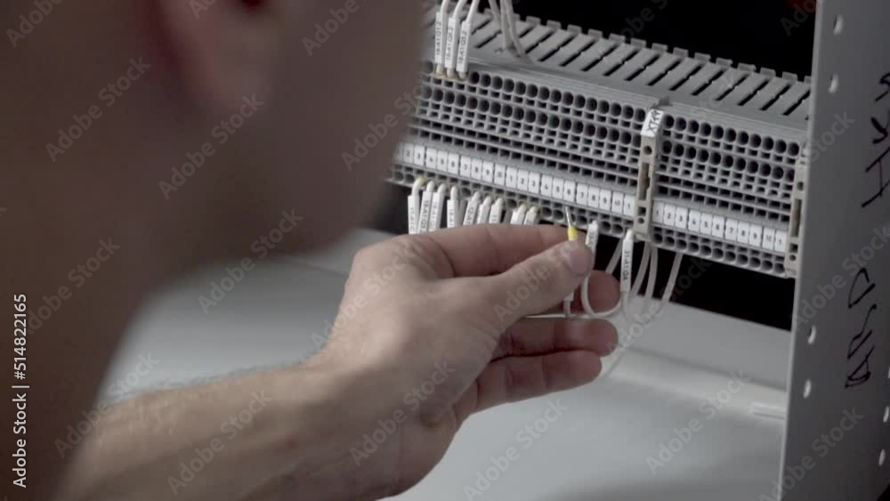 Electrical engineer installs cables in Electrical panel with many wires ...
