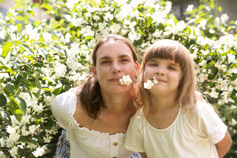 mom and little daughter holding and inhaling jasmine scent amid ...