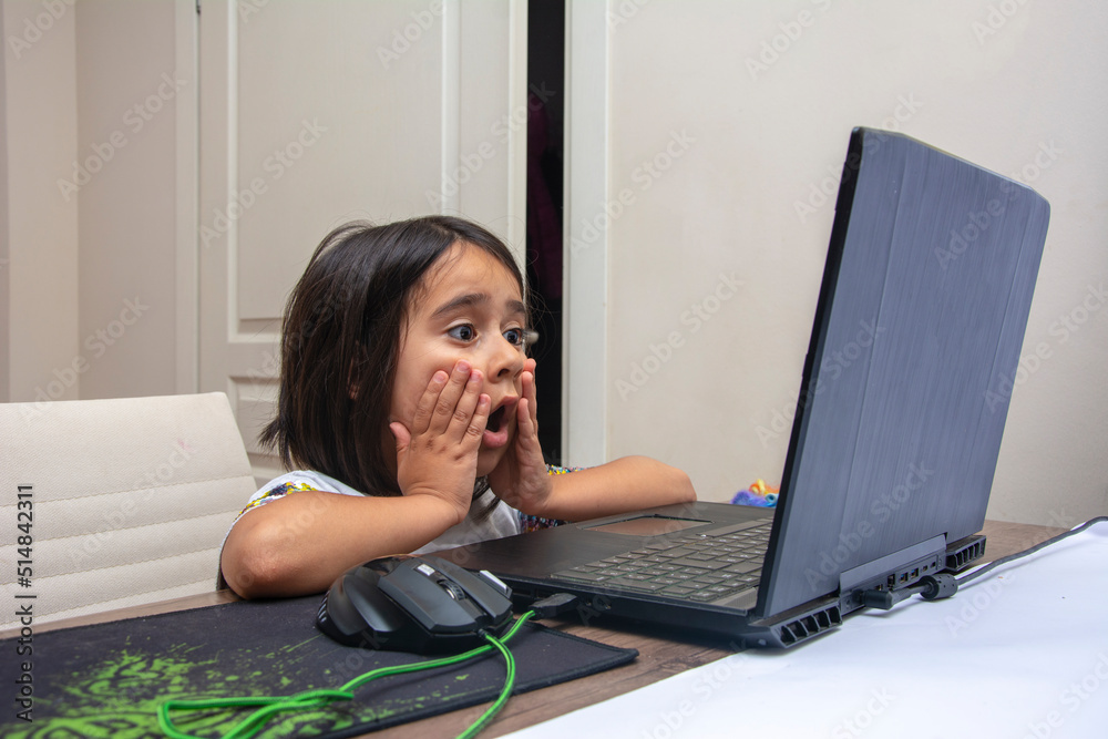 Little girl is shocked by what she sees on the computer screen Stock ...
