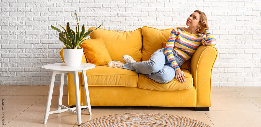 Beautiful young woman relaxing on sofa at home Stock Photo | Adobe Stock
