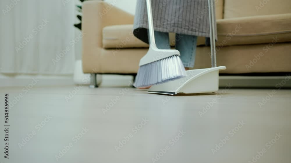 Close Up Hand Of Housewife Using Broom And Dustpan Wearing An Apron To