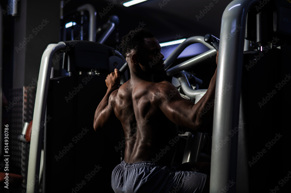 Shirtless african american man doing back exercises on a machine in the ...