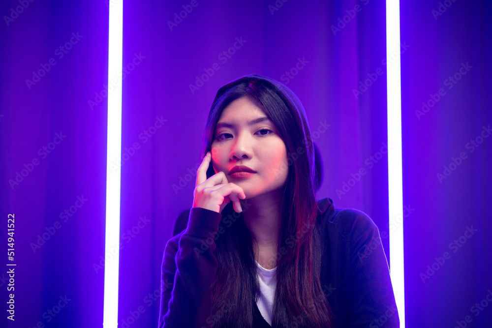 Pro gamer. Young pretty asian woman sitting pose to camera with neon ...
