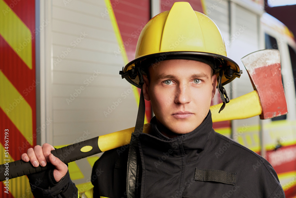 Firefighter fully equipped with helmet and ax in fire truck background ...