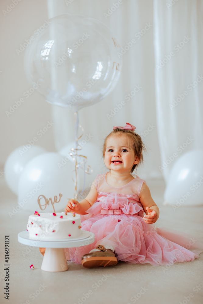 Cute one year girl in pink beautiful dress and cute little bow posing ...