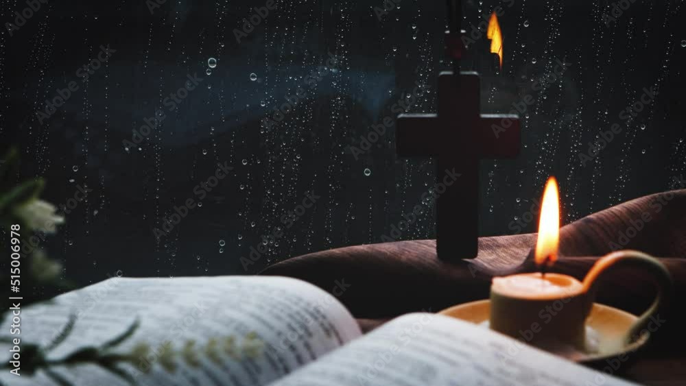 Rain falling on the window and flowing raindrops, cross, candle and ...