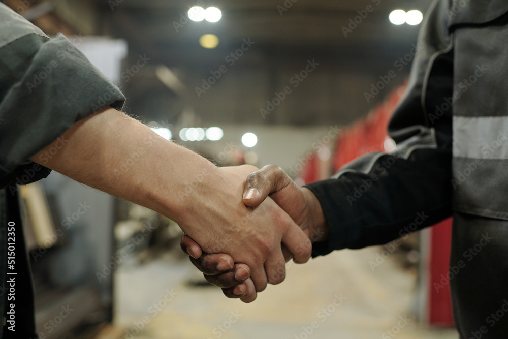 Handshake of two young intercultural workers of factory greeting each ...