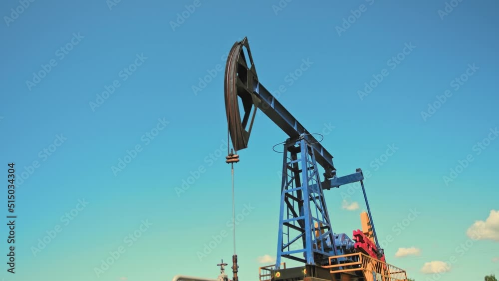 Close-up low angle shot of working oil pump rig at sunny day. Oil and ...
