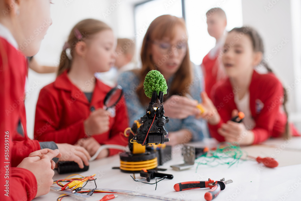 Group of kids with young science teacher programming electric toys and ...