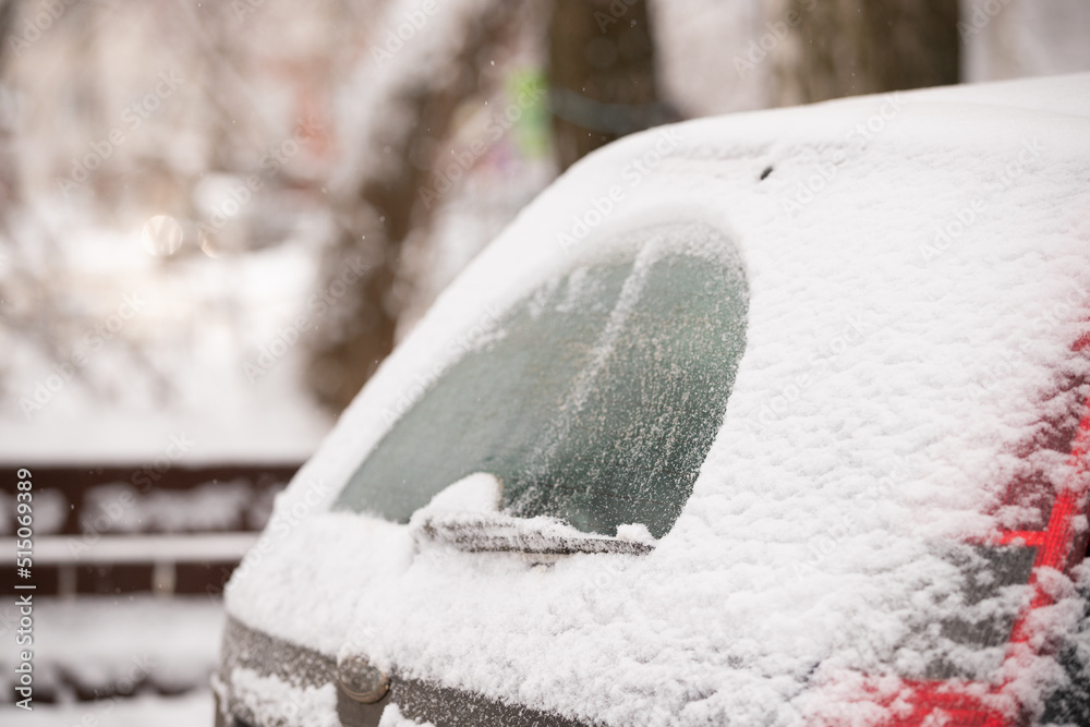 Snow suddenly fell on cars and roads. A car wiper cleans the rear glass ...