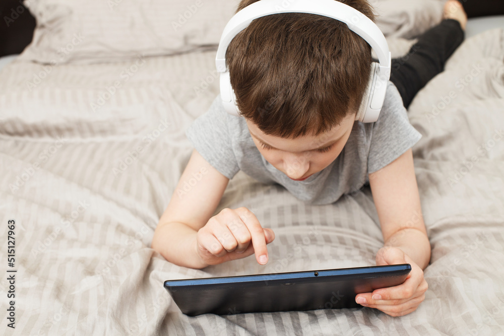 child boy lying on bed with pc tablet with wireless headphones Stock ...