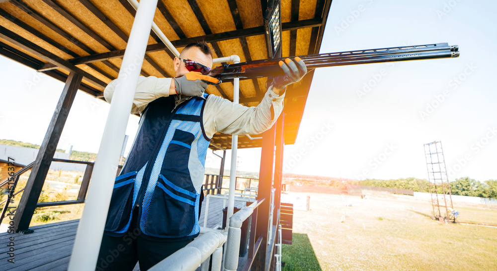 Adult man in sunglasses and a rifle vest practicing fire weapon ...