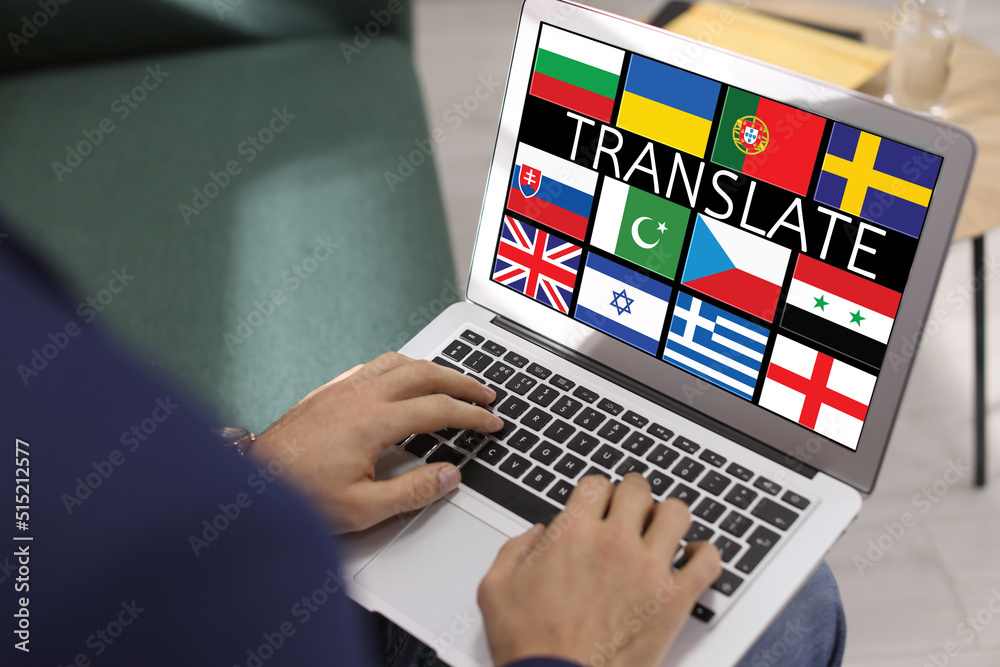 Foto de Translator using modern laptop with images of different flags ...
