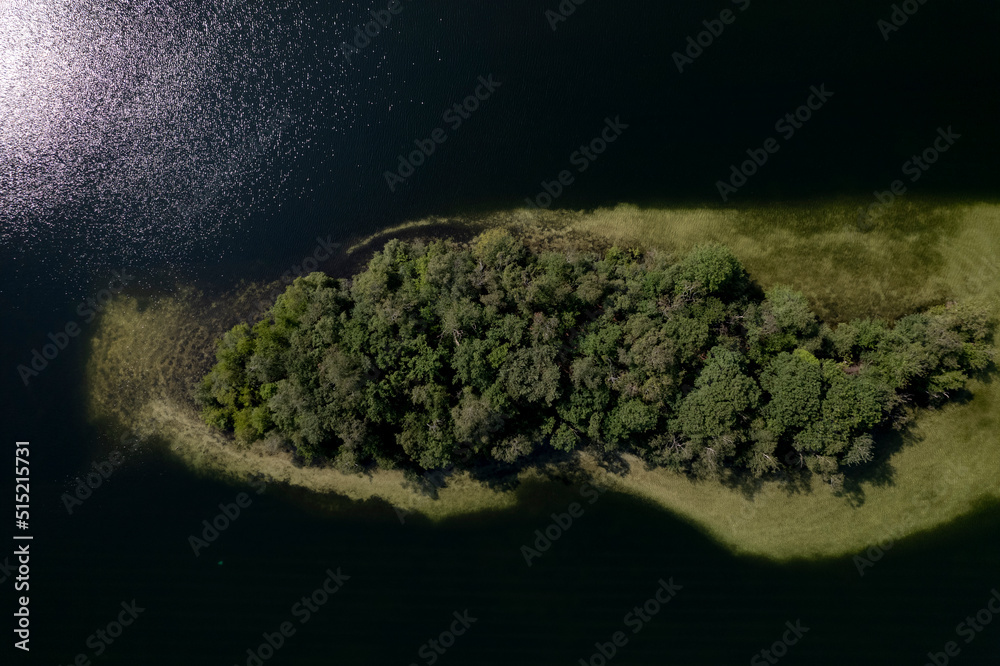 Sunspot reflection in the water of green island top down aerial view in ...
