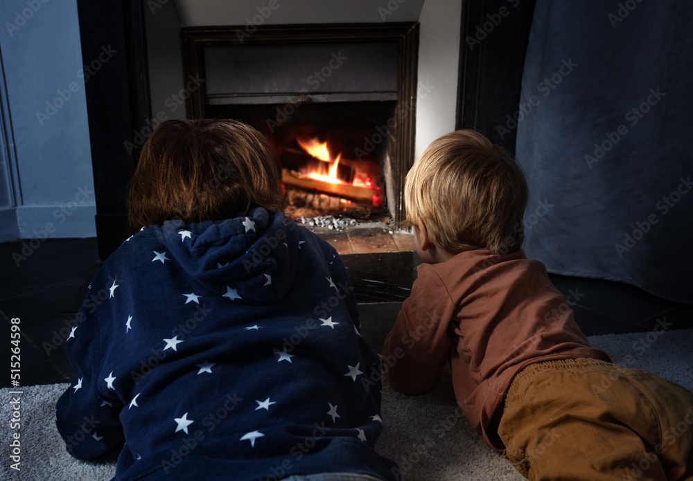 Two boys lay in front of the home fireplace look at fire Stock Photo ...