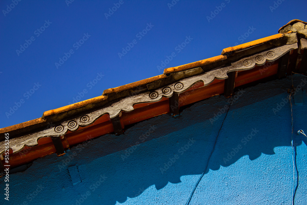 Detalhe de telhado de uma casa pintada de azul e com o céu azul ao ...
