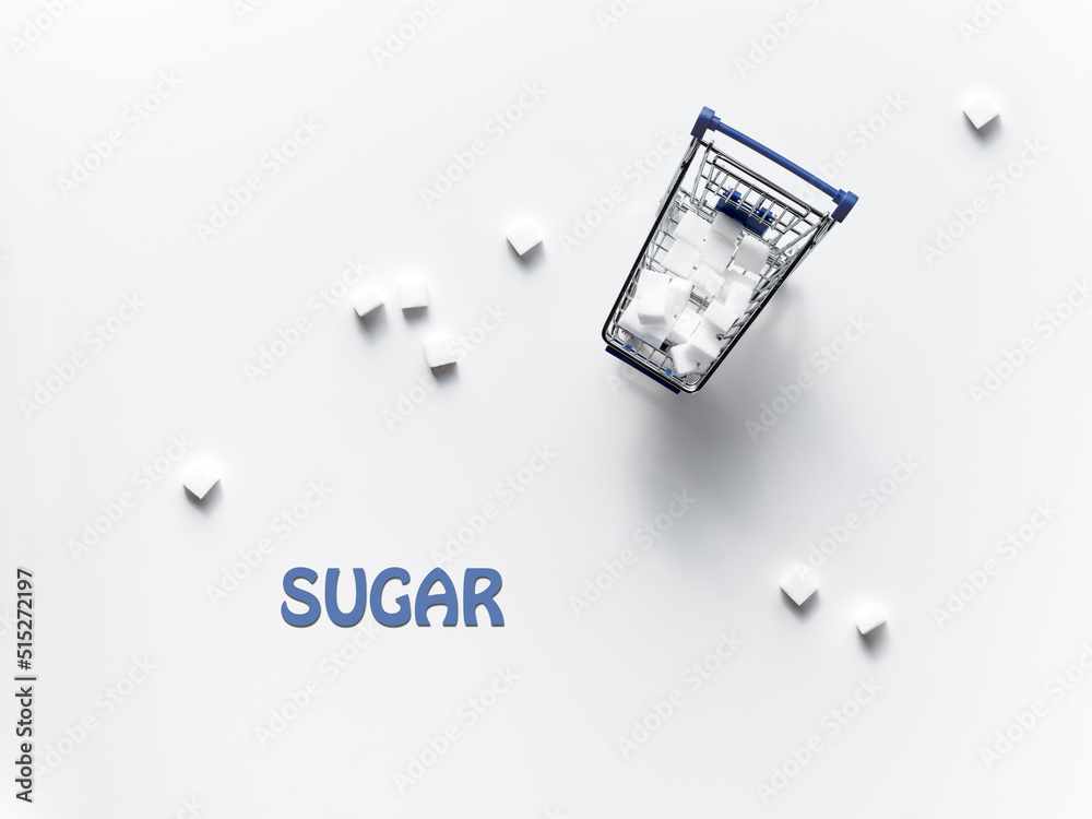 Text Sugar, shopping trolley with rafinade pieces, lumps of sugar on ...