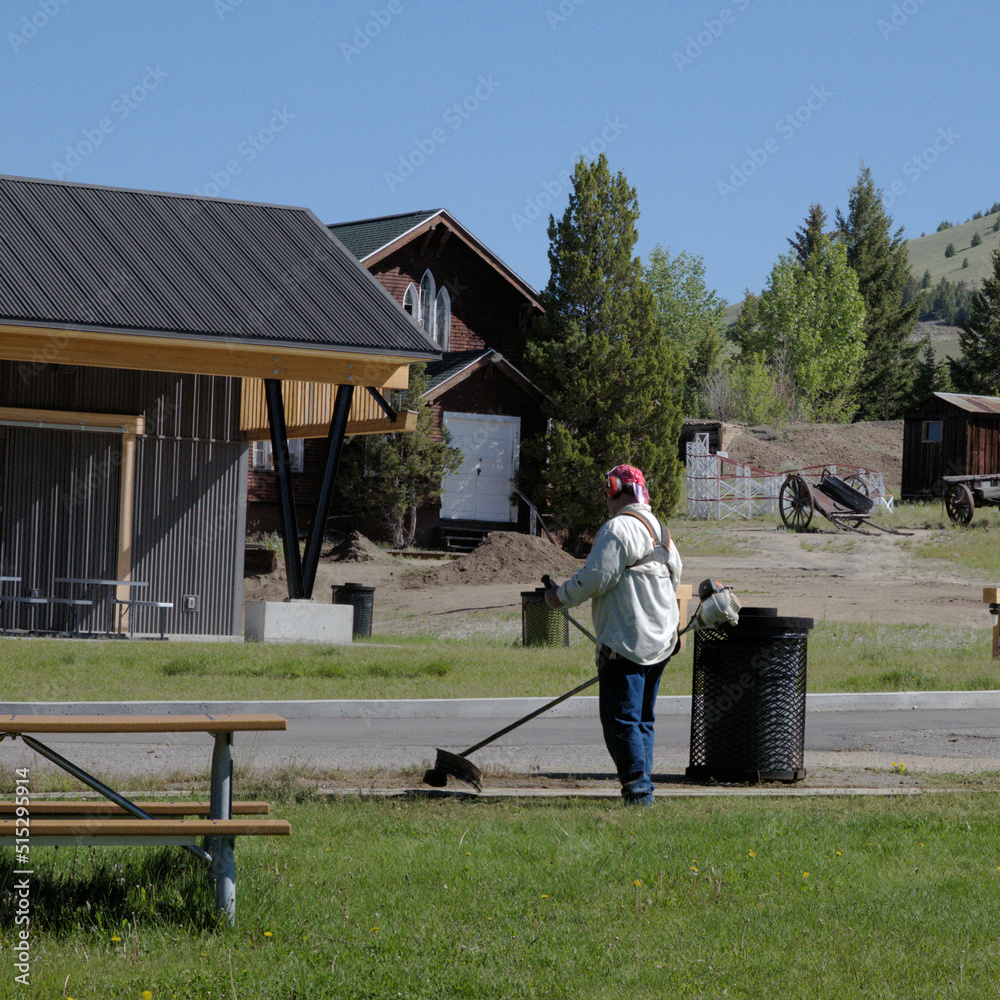 Unknown park worker using gas trimmer to keep the grounds neat and ...