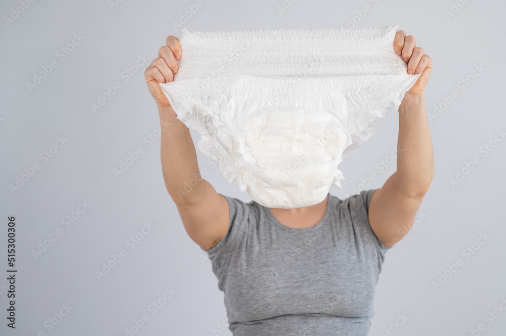 A caucasian woman holds an adult diaper and checks its strength on a ...