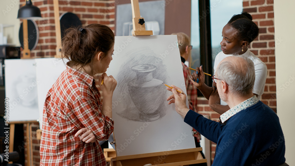 Elder student talking to people in art class about drawing technique ...