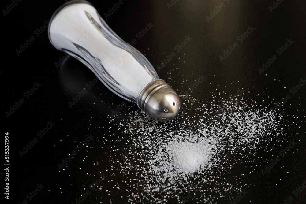 glass salt shaker and salt grains on black background Stock Photo ...