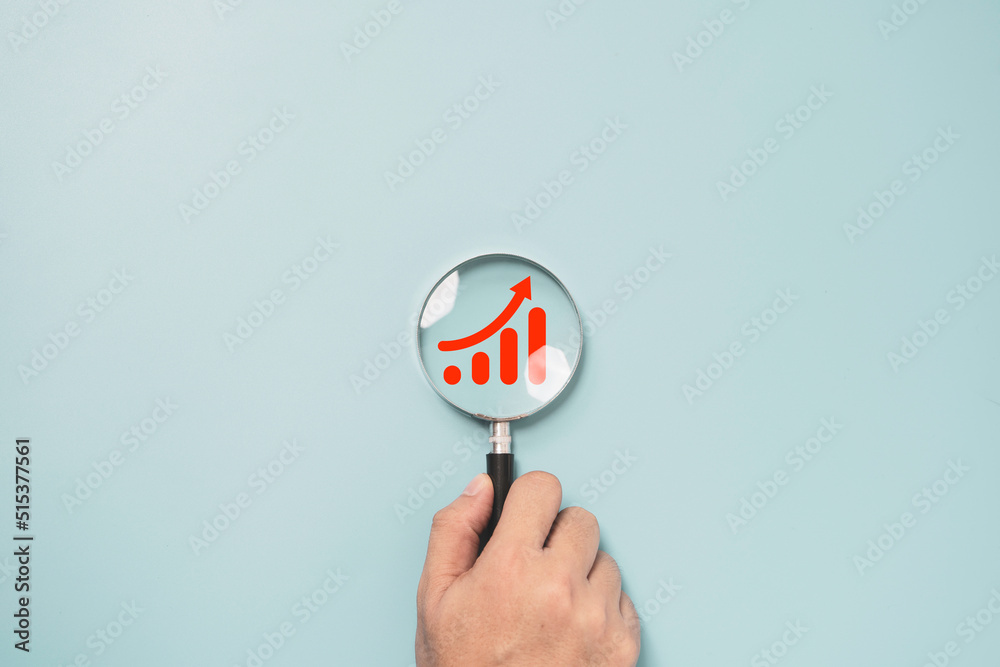 Hand holding magnifier glass with red growth graph and chart with copy ...