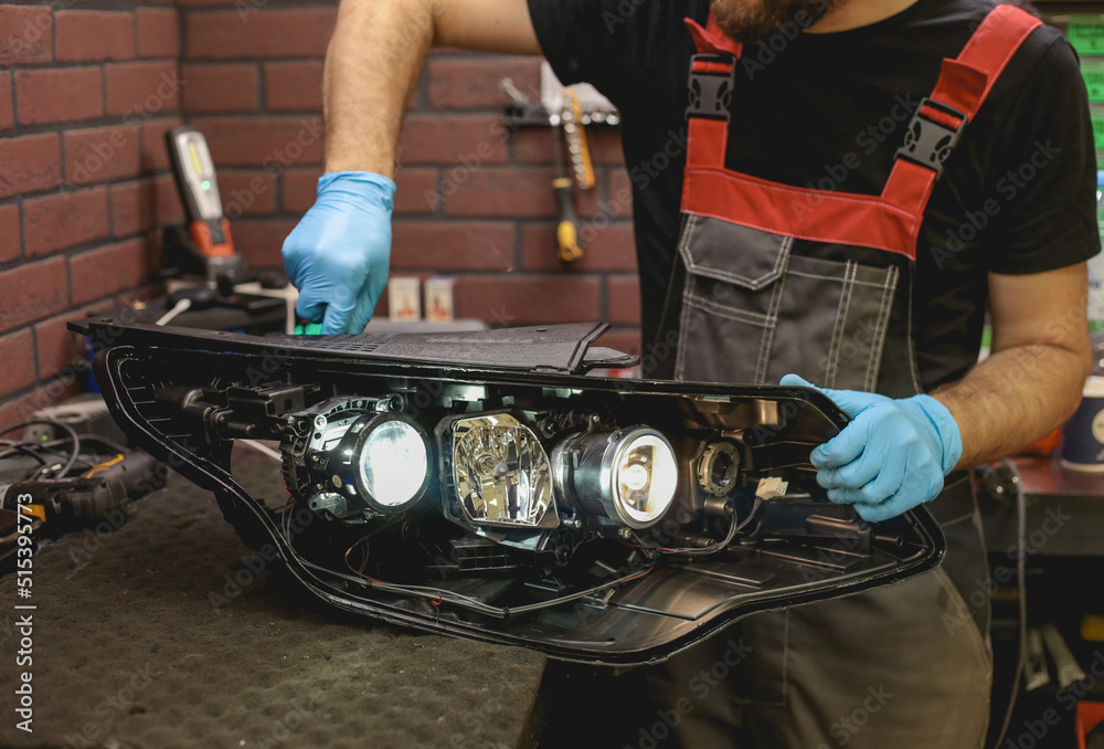 Car headlight in repair close-up. The car mechanic installs the lens in ...