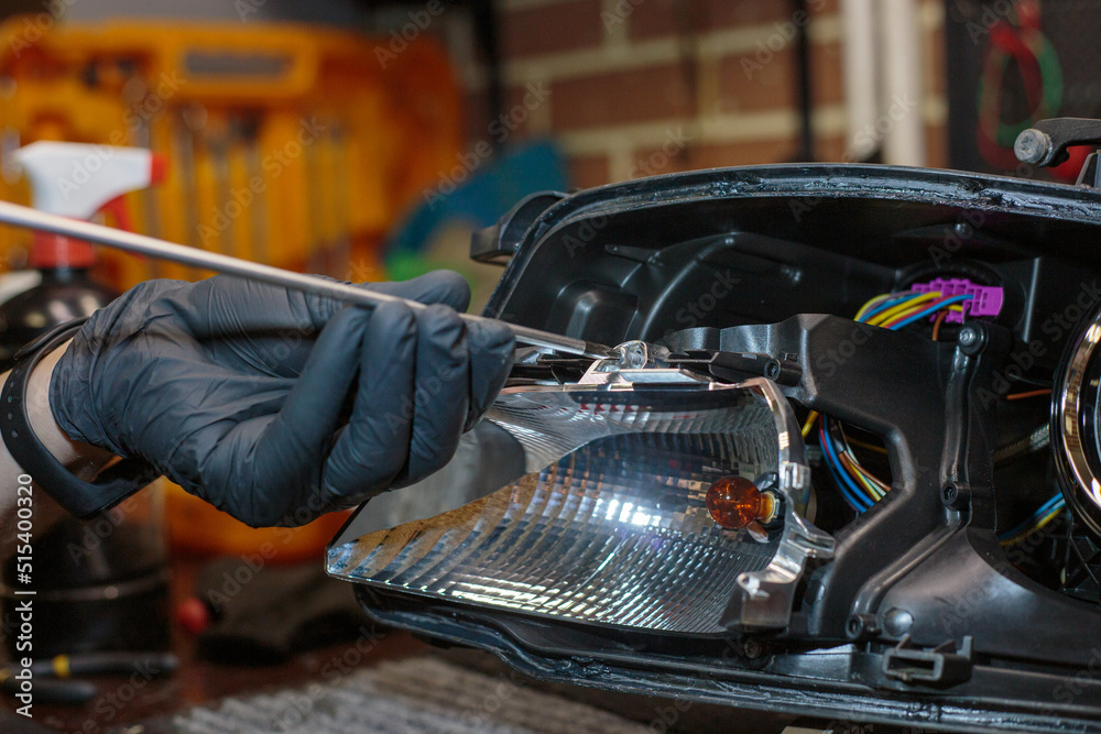 Car headlight in repair close-up. The car mechanic installs the lens in ...