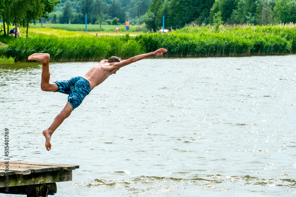 Teenagers jump into the water and swim in the lake on a hot summer day ...