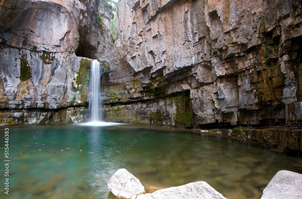 Hidden waterfall pouring into a turquoise pool in a secluded rock ...