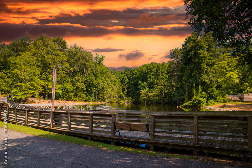 a gorgeous summer landscape in the park with a lake and a brown wooden ...