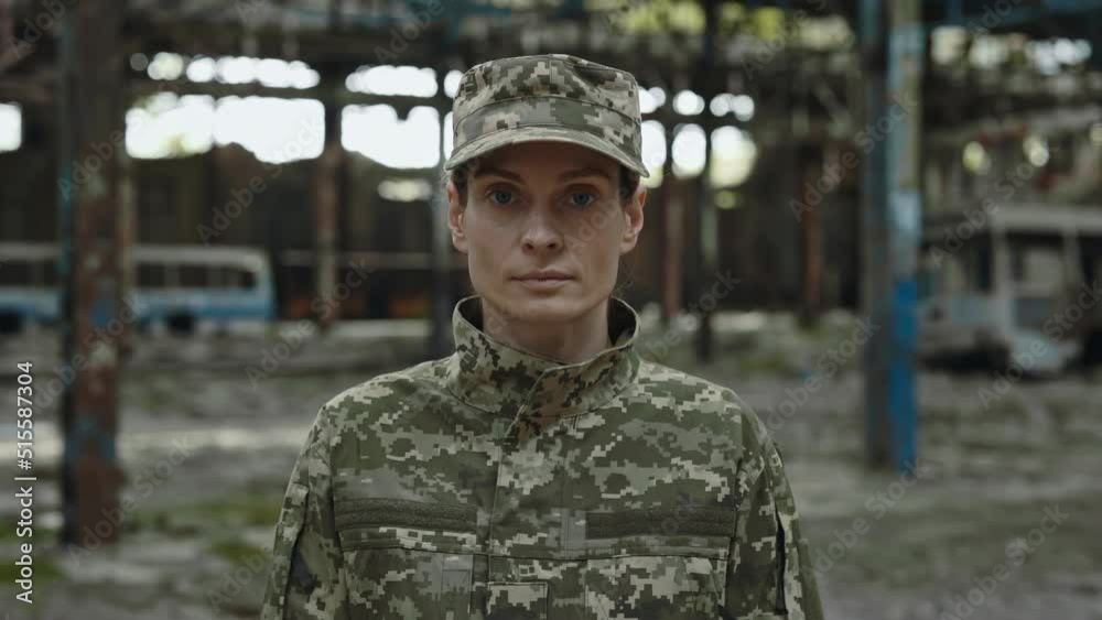 Beautiful female soldier standing and looking at camera with serious ...