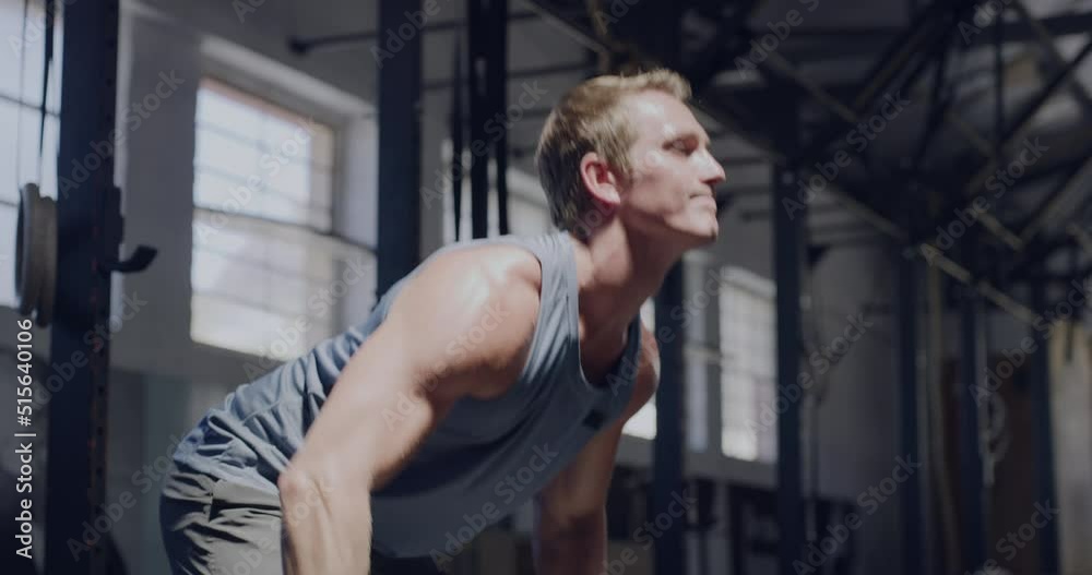 Muscular man lifting a barbell while doing bent over rows in a gym. Fit ...