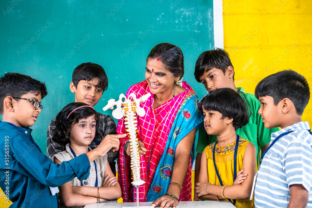 Teacher with human spine biological model explaining to students during ...