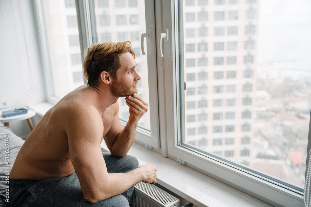 Young white shirtless man sitting in thoughtful position at home Stock ...