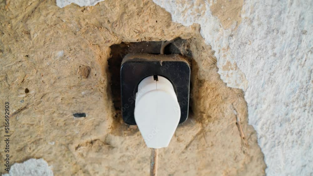 Video „A white plug is inserted into an old socket in the clay wall of ...