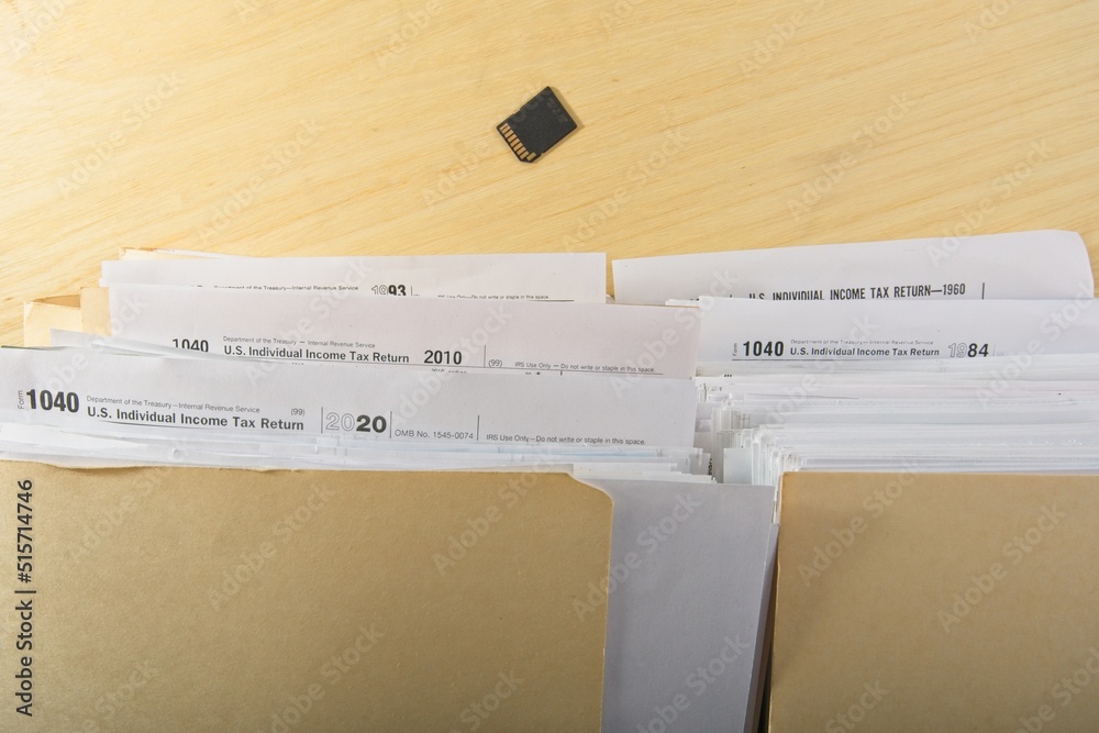 Lifetime stack of paper U.S. tax returns tower over Secure Digital data ...