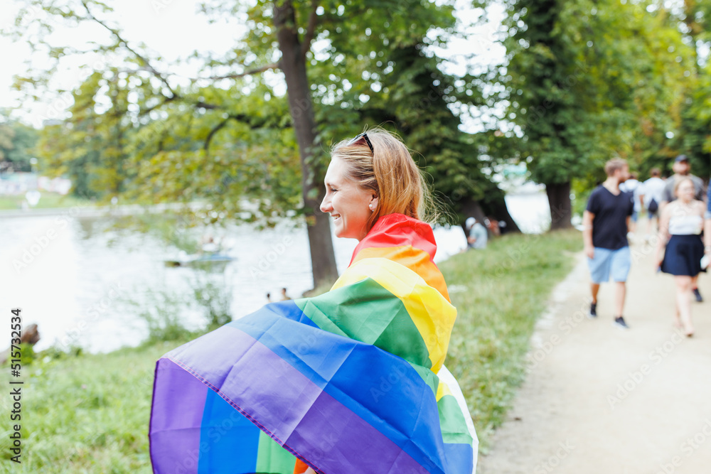 Happy young blonde hair woman covering with LGBTQI pride rainbow flag ...