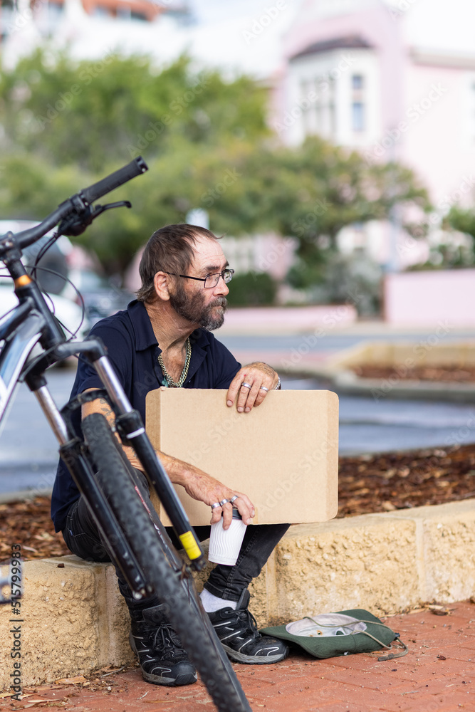 homeless man with bicycle sitting on low wall with cardboard sign Stock ...