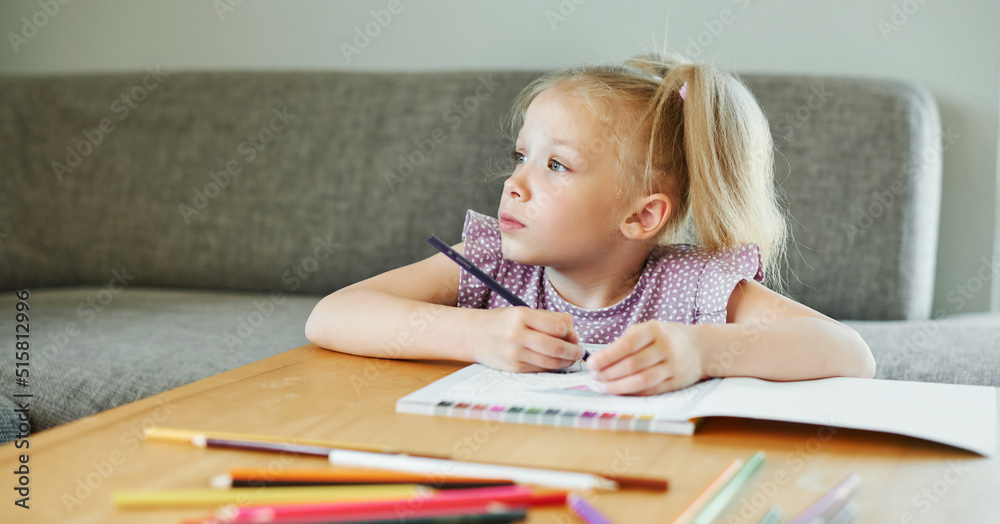 Sad child girl learning to draw sitting at home table. Portrait of ...