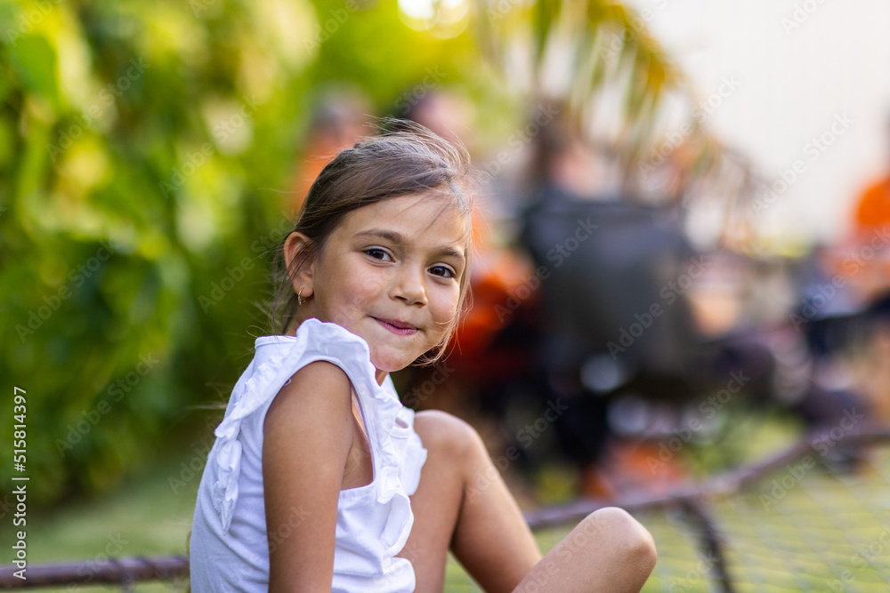 little girl smiling looking at camera over shoulder, with adults ...