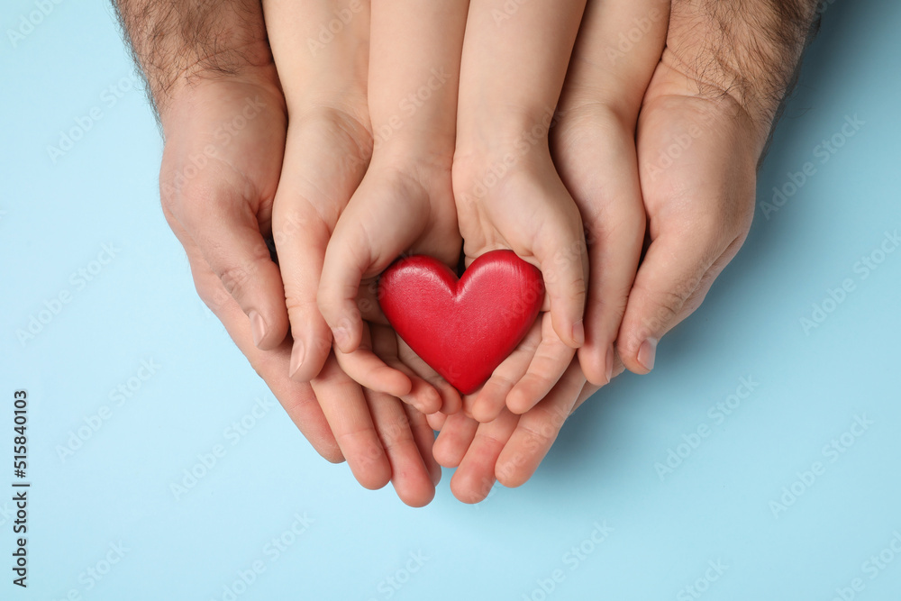 Parents and kid holding red heart in hands on light blue background ...