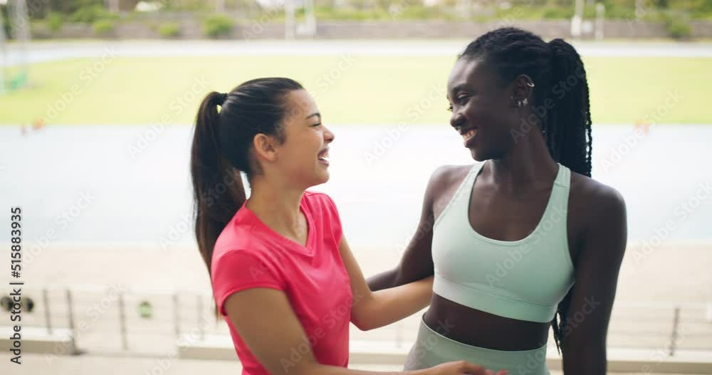Two happy female athletes greeting each other at a sports ground ...