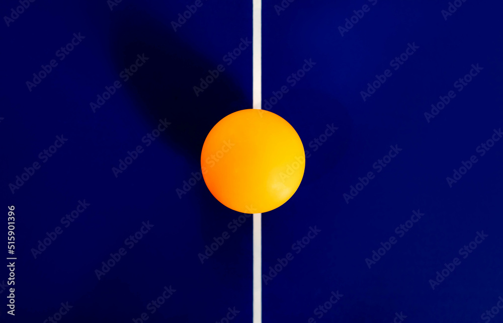 An orange ping pong ball flat lay at the center of the white line on ...