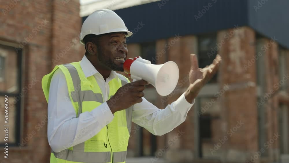 Expressive african american foreman in safety helmet shouting into ...