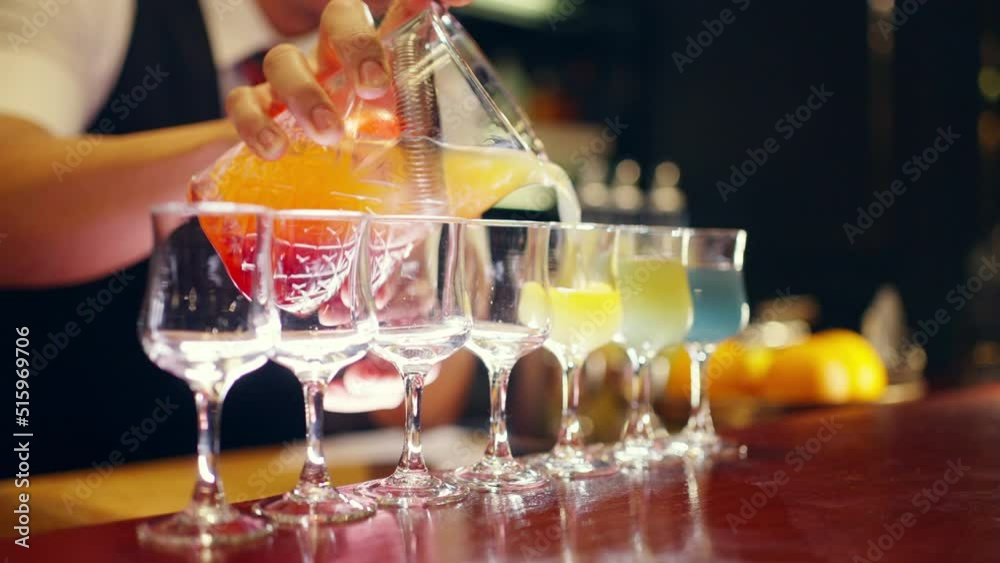 4K Male bartender preparing and pouring mixed colorful cocktail drink ...